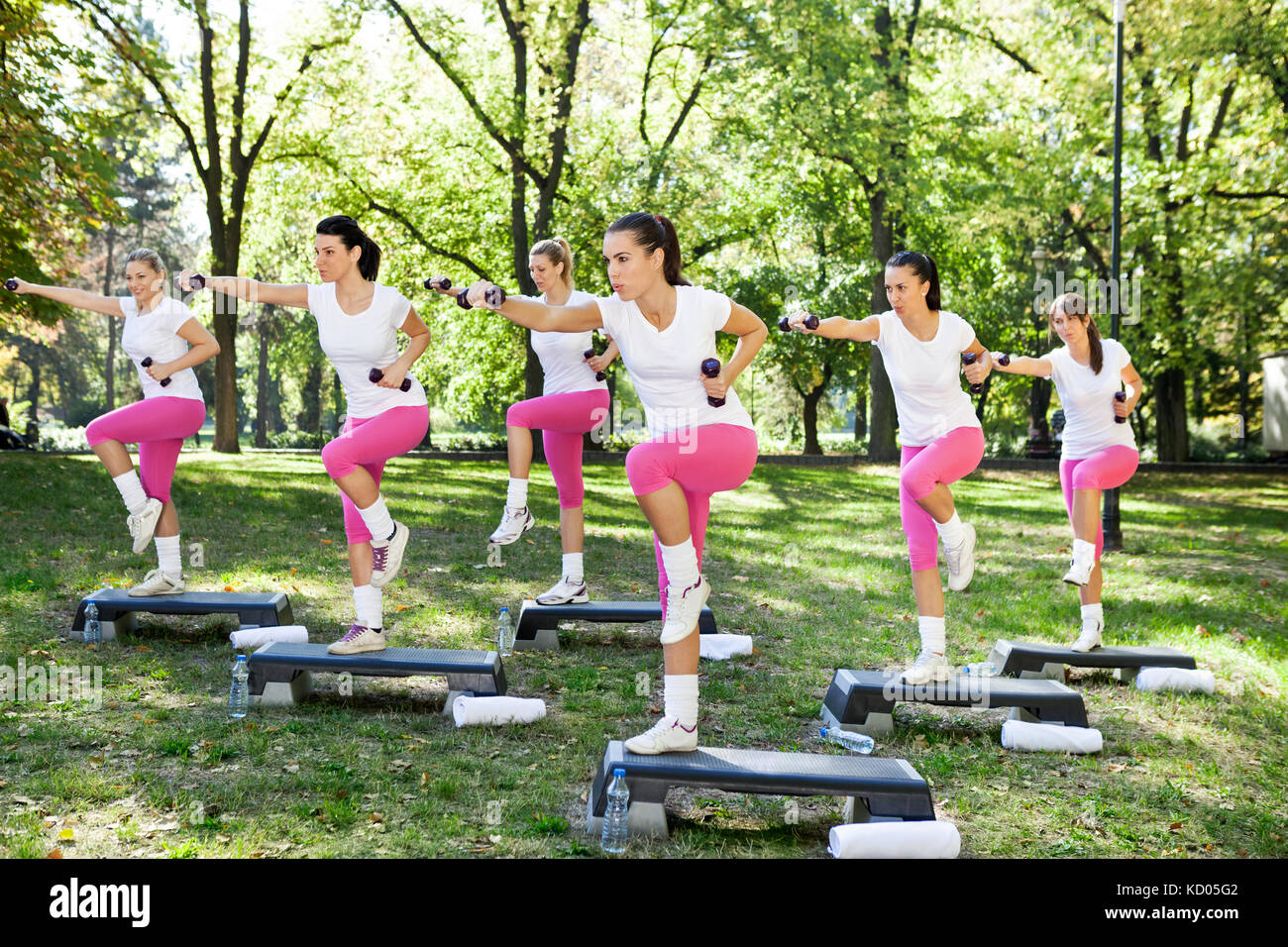 group of a young women doing exercises with dumbbell on a sunny day ...