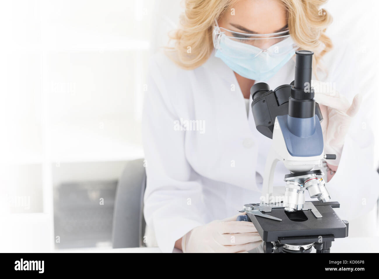 Female doctor looking through a microscope, studio shot isolated on ...