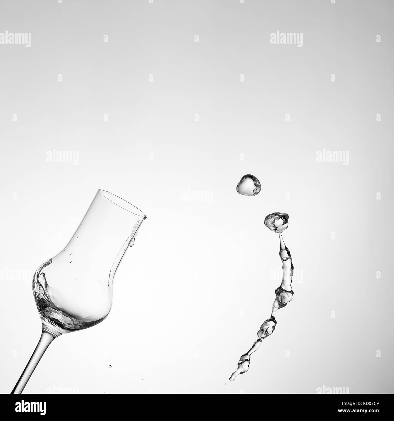 Shot glass with splash and drops of grappa in the backlight Stock Photo ...