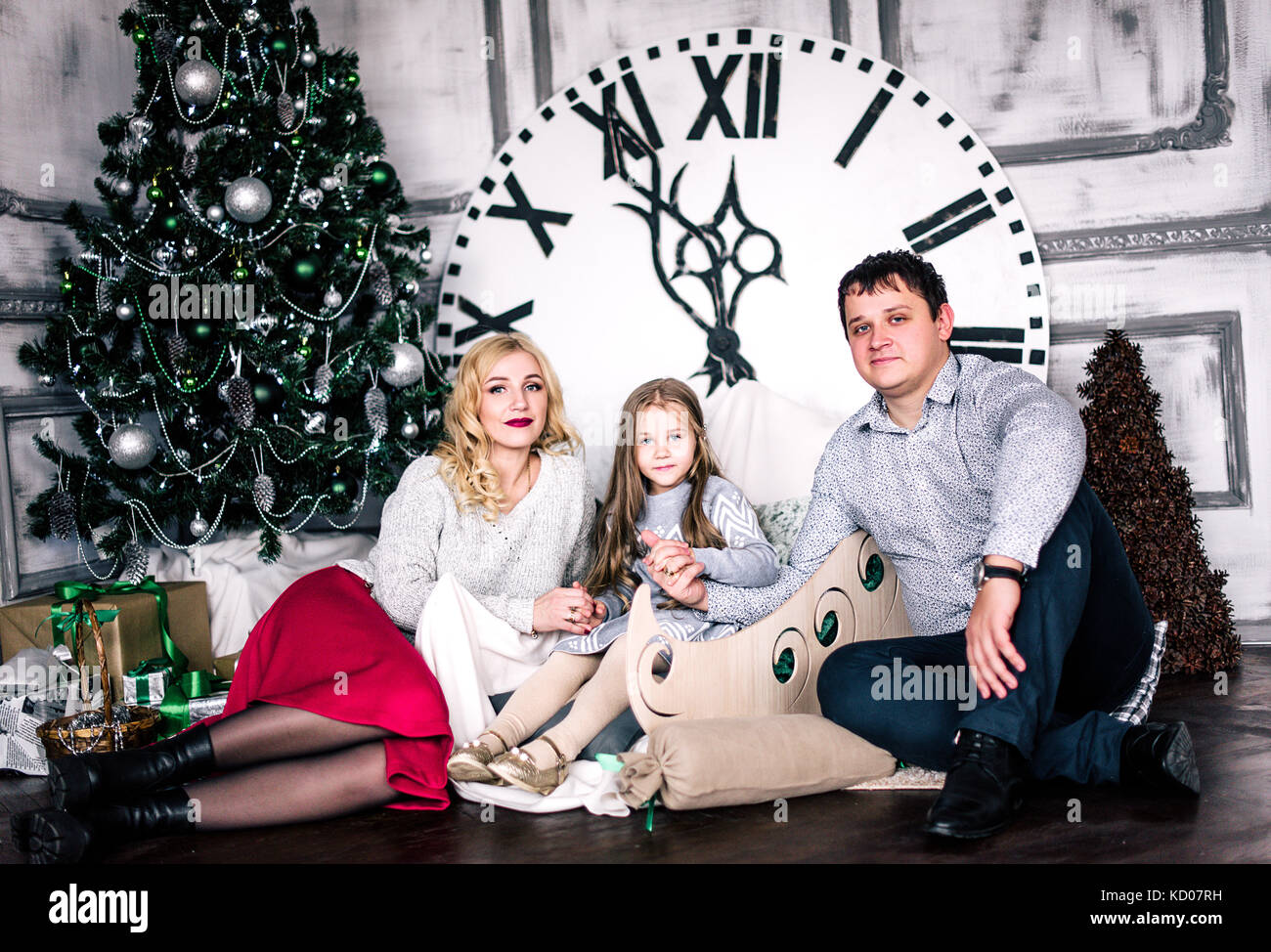 Family gathering together near the christmas tree. The clock in the ...