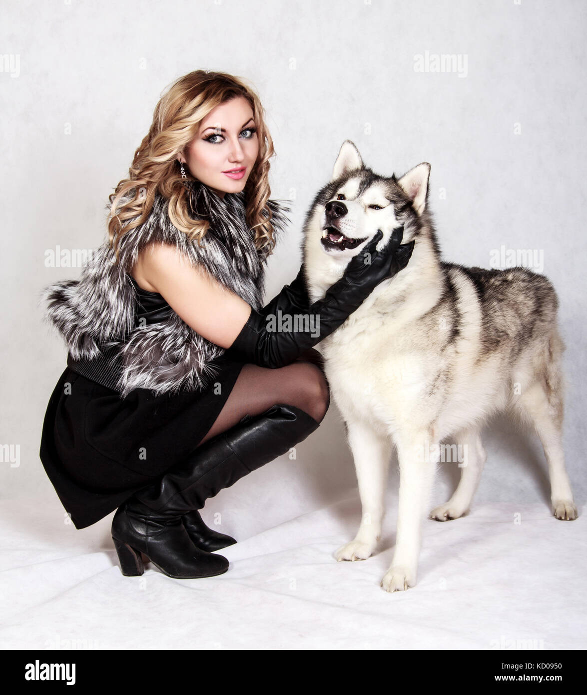 Beautiful young woman with a husky dog over grey background Stock Photo ...