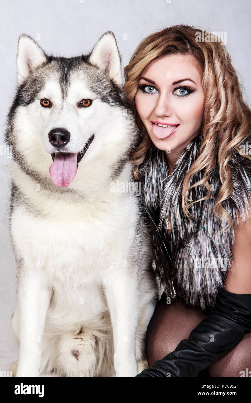 Beautiful young woman with a husky dog over grey background Stock Photo ...