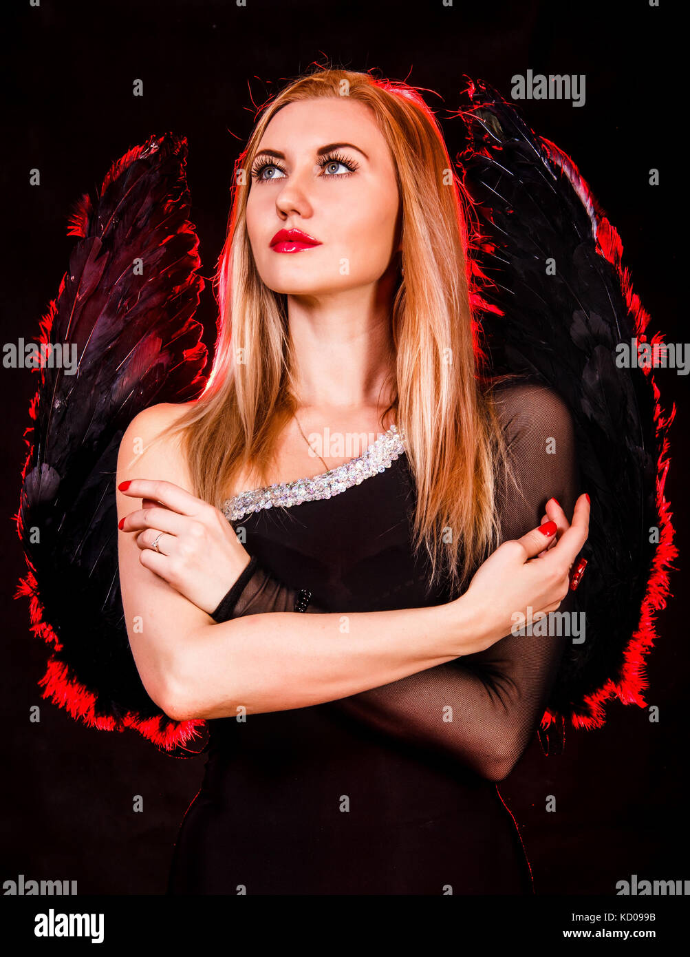 Beautiful young woman with black angel wings over black background ...