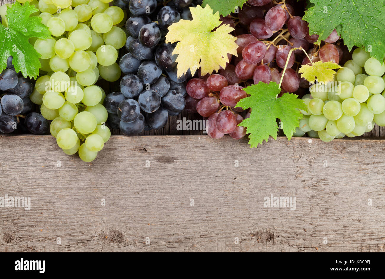 Various colorful grapes on wooden background. With space for your text ...