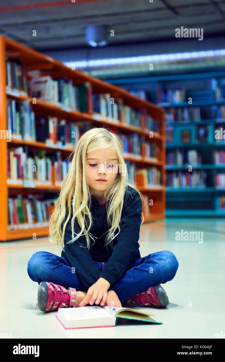 Child girl in public library with book Stock Photo - Alamy