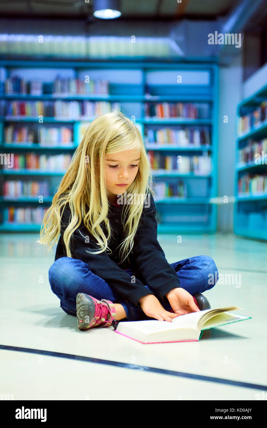 Child girl in public library with book Stock Photo - Alamy