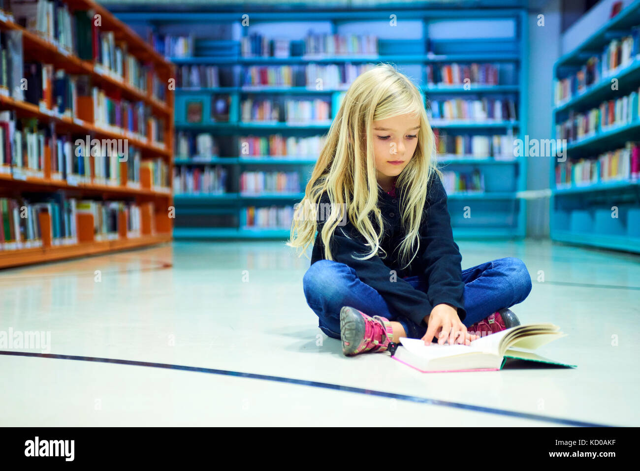 Child girl in public library with book Stock Photo - Alamy