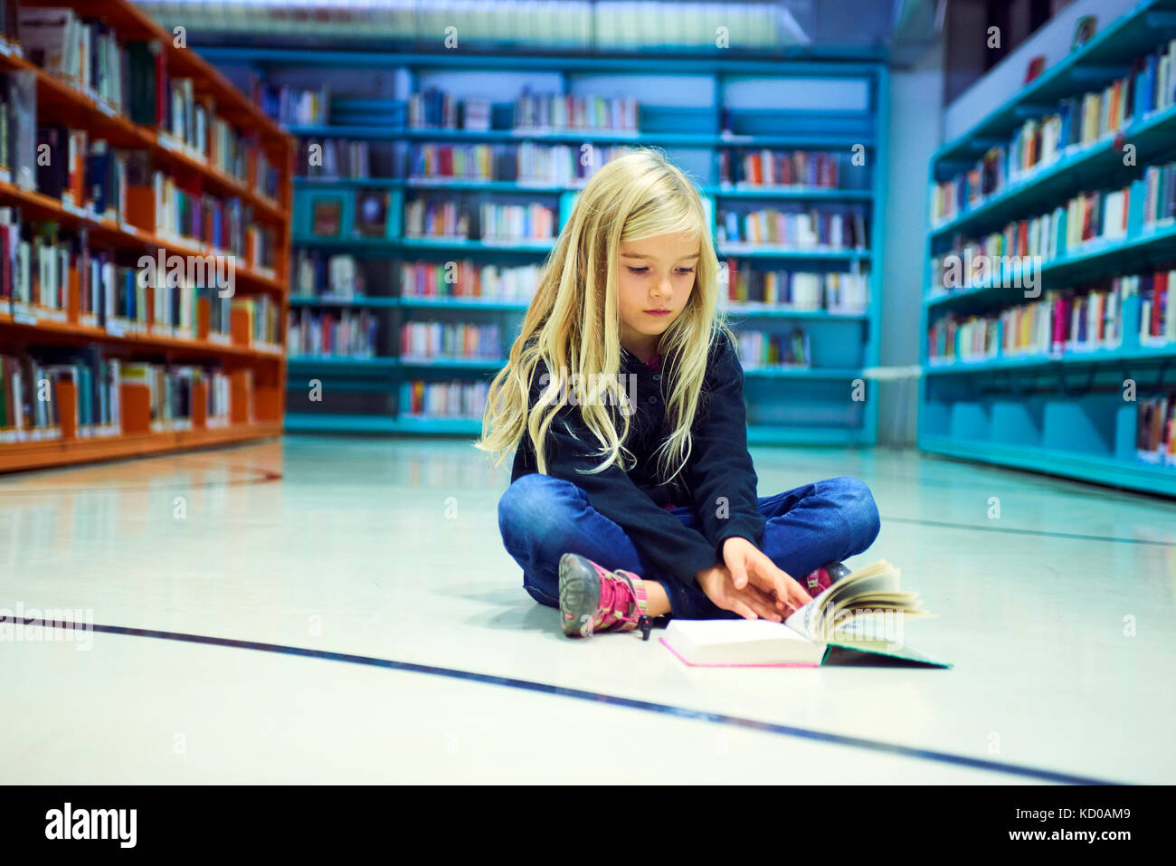 Child girl in public library with book Stock Photo - Alamy