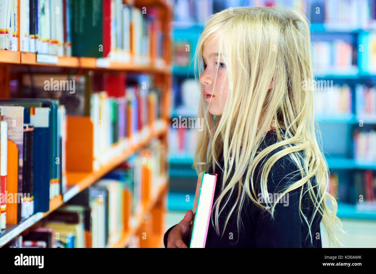 Child girl in public library with book Stock Photo - Alamy