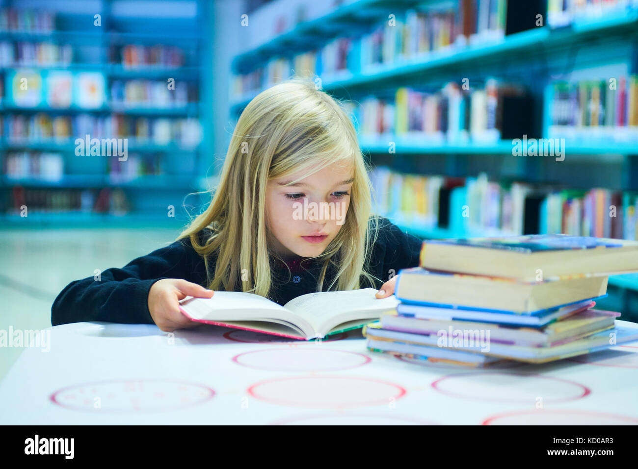 Child girl in public library with book Stock Photo - Alamy