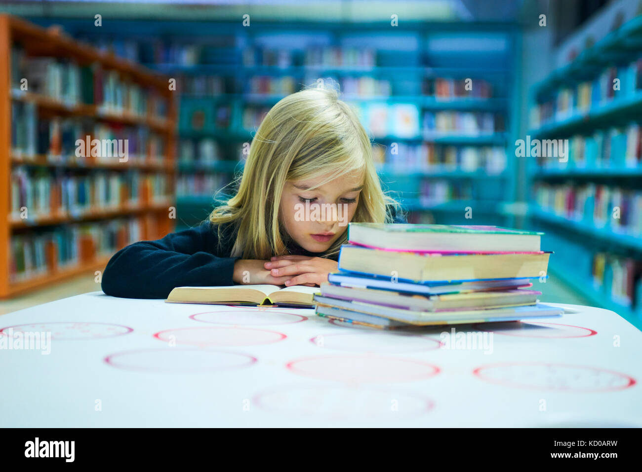 Child girl in public library with book Stock Photo - Alamy