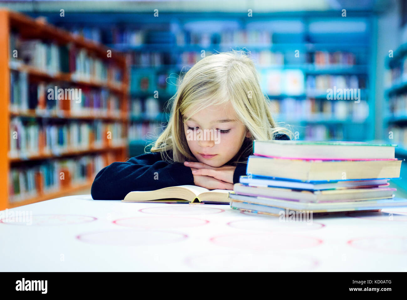 Child girl in public library with book Stock Photo - Alamy
