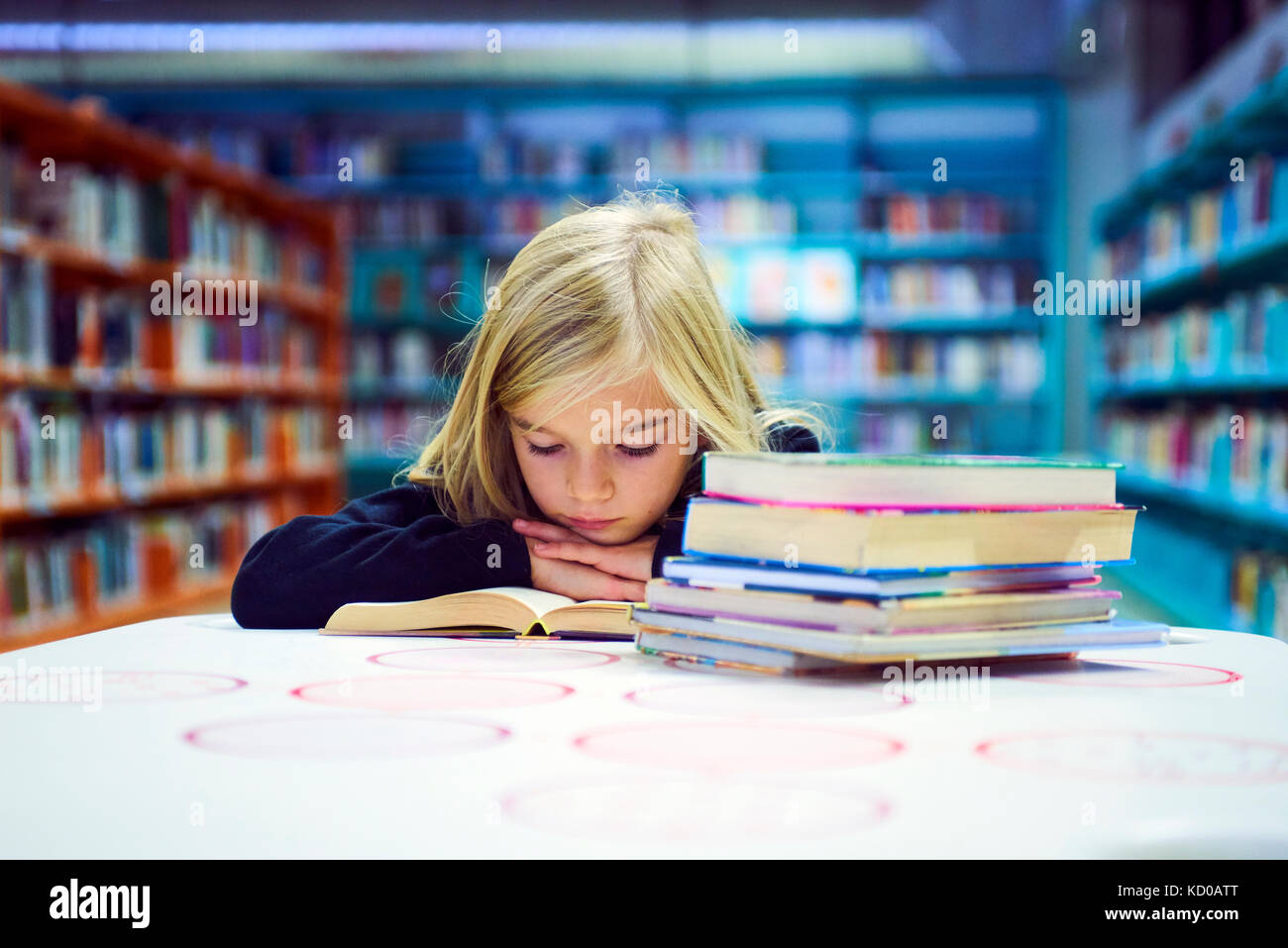 Child girl in public library with book Stock Photo - Alamy