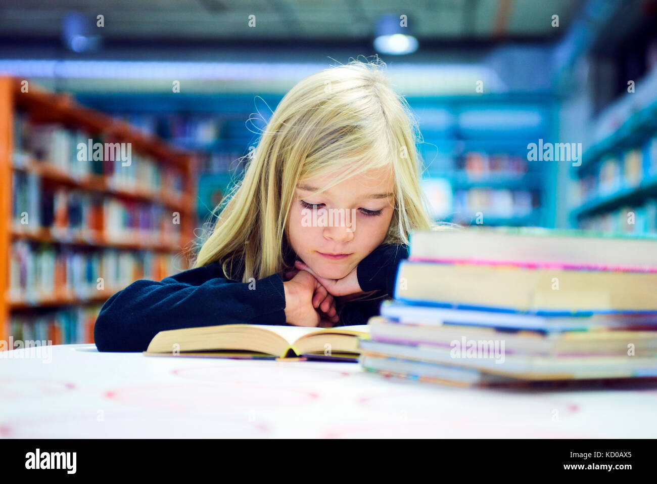 Child girl in public library with book Stock Photo - Alamy