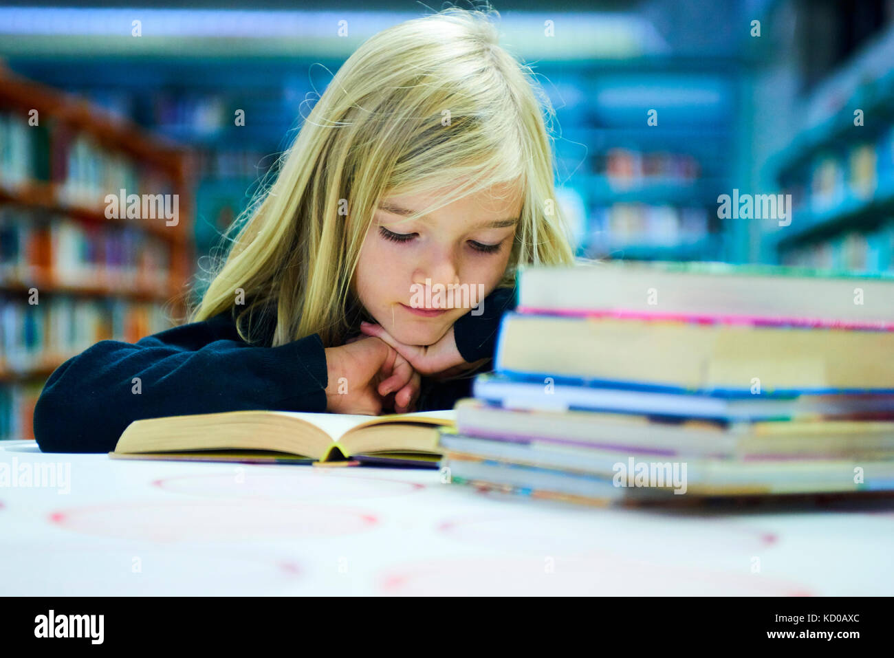 Child girl in public library with book Stock Photo - Alamy