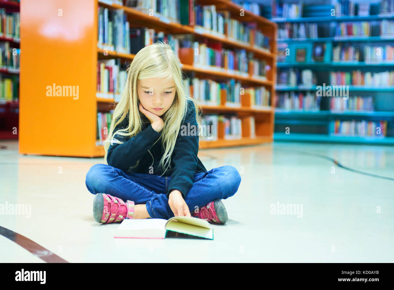Child girl in public library with book Stock Photo - Alamy