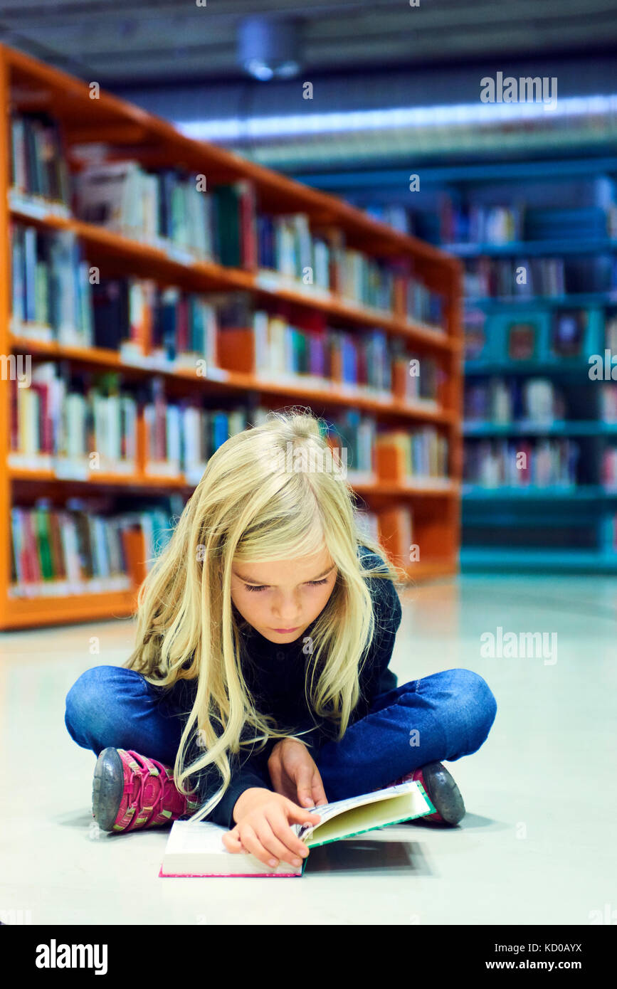 Child girl in public library with book Stock Photo - Alamy
