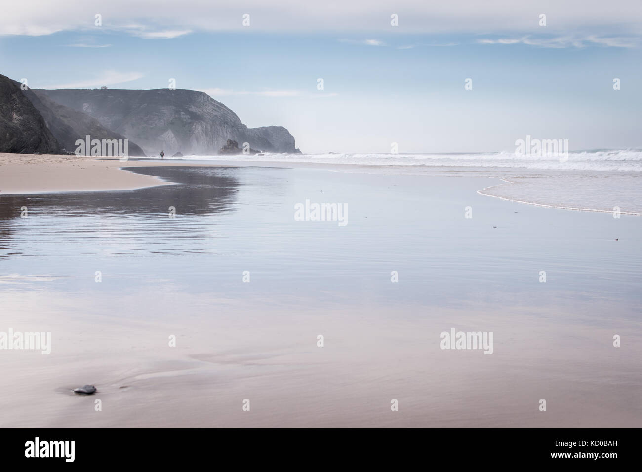 Sandy beach with water reflections and rocks in the background Stock ...