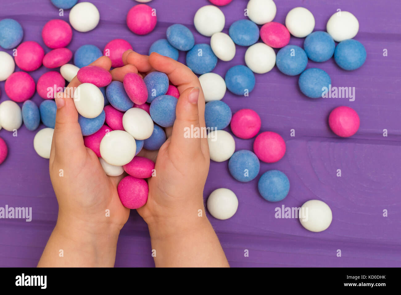 Children's hands holding colored candies Stock Photo - Alamy