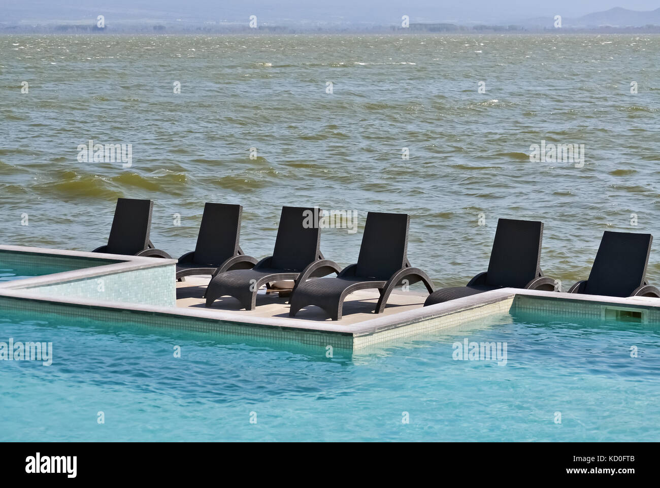 Swimming pool by the lake and sunbeds in a windy summer day Stock Photo ...