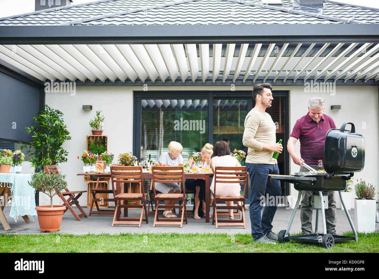 Two men barbecuing on patio at family lunch Stock Photo - Alamy