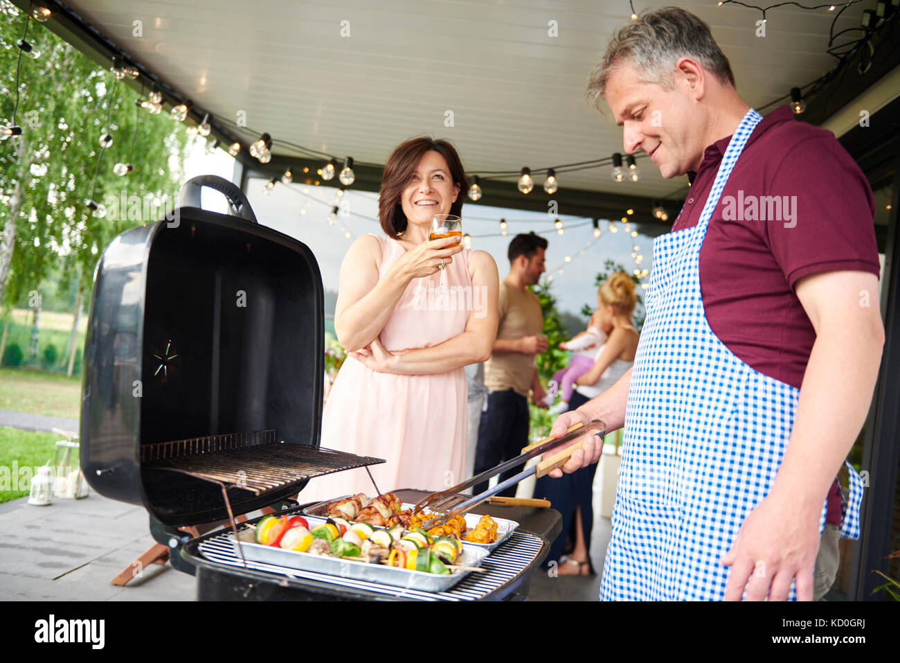 Mature couple barbecuing at family lunch on patio Stock Photo - Alamy