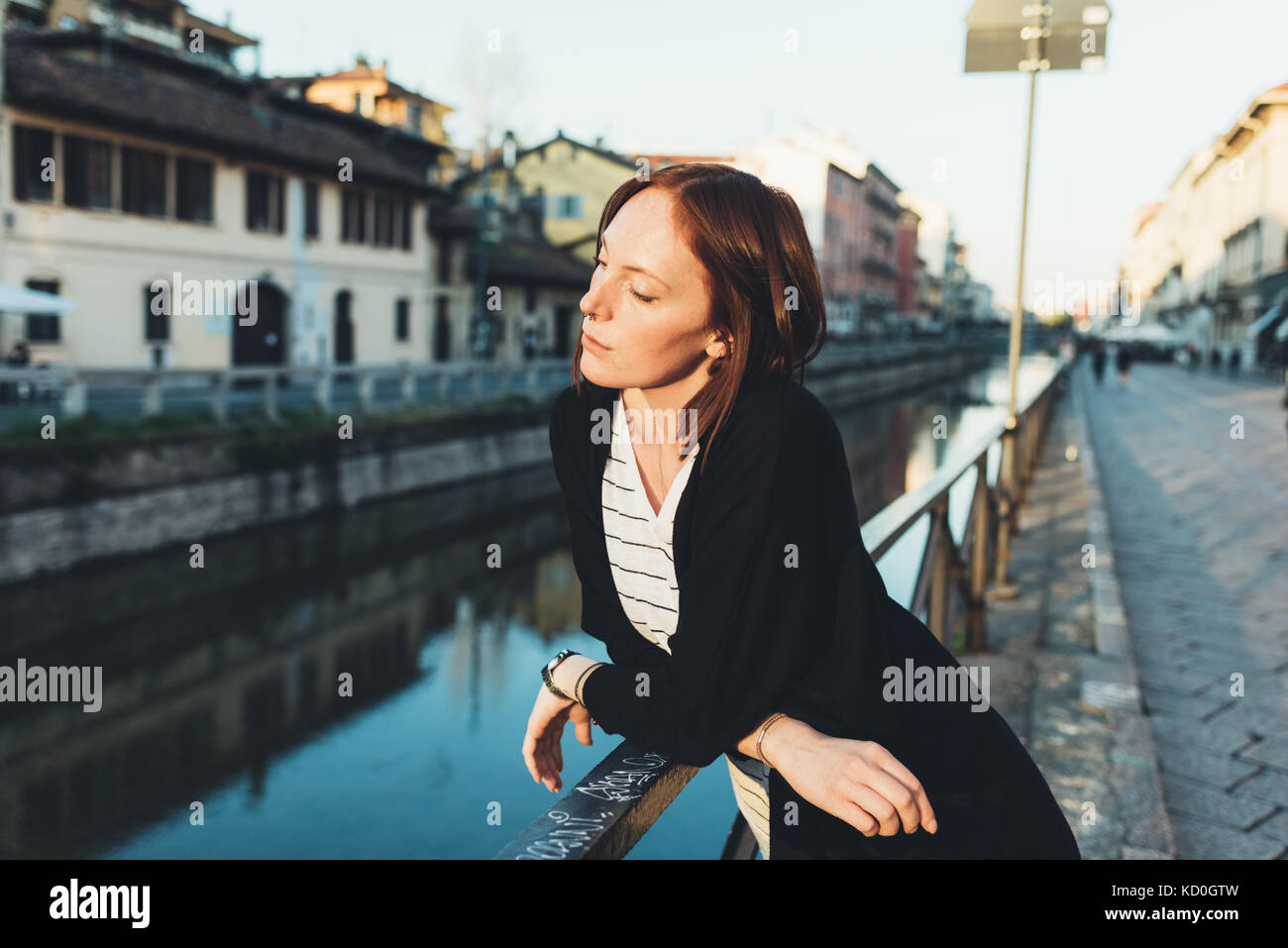 Young woman leaning against railing looking down at canal Stock Photo ...
