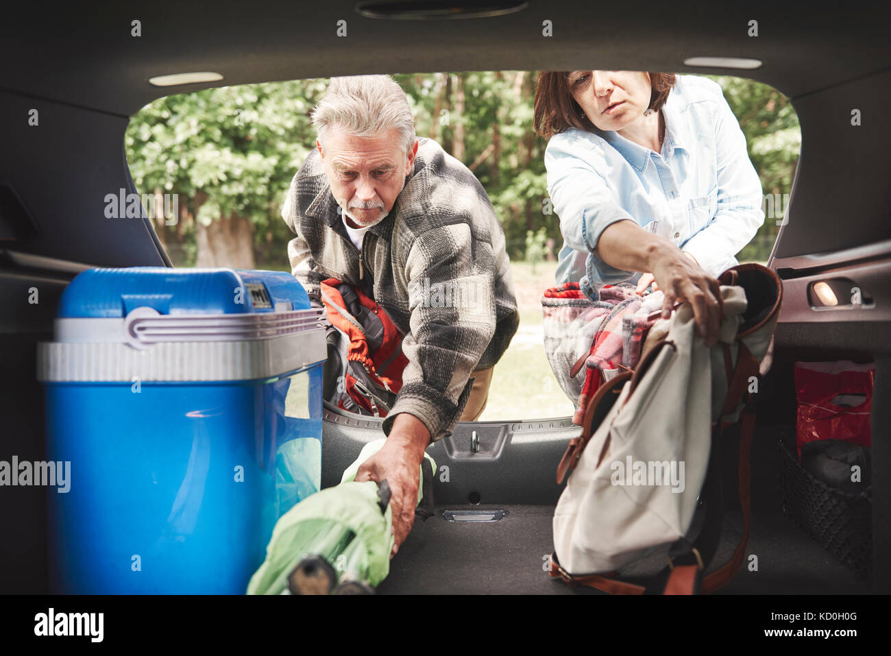 Mature couple removing camping equipment from car boot Stock Photo - Alamy
