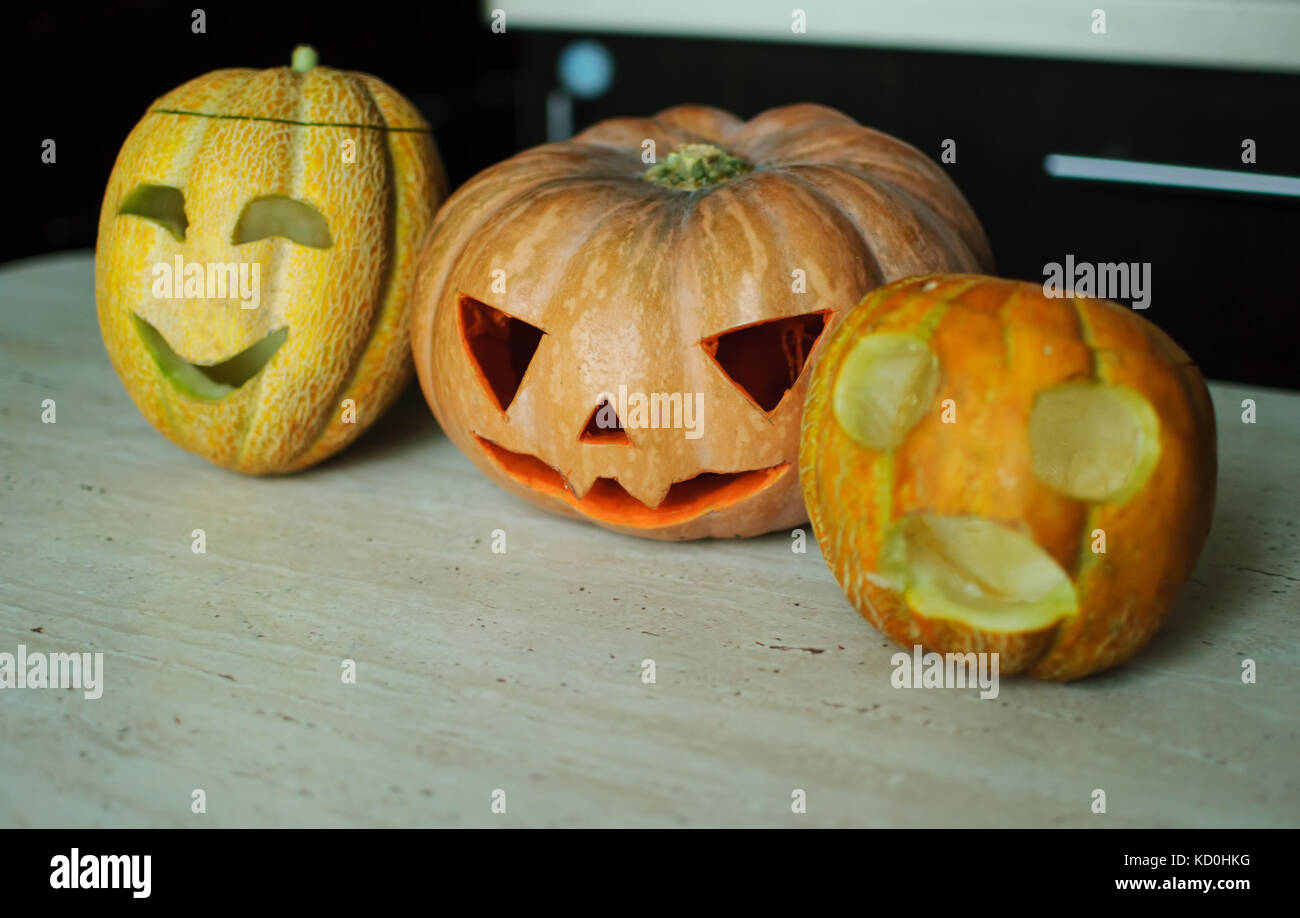 Three jack-o'-lanterns from pumpkin and melons on kitchen table ...