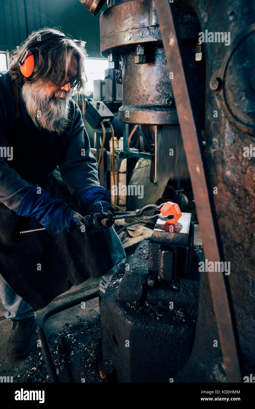 Blacksmith using blacksmith tongs for red hot metal Stock Photo - Alamy