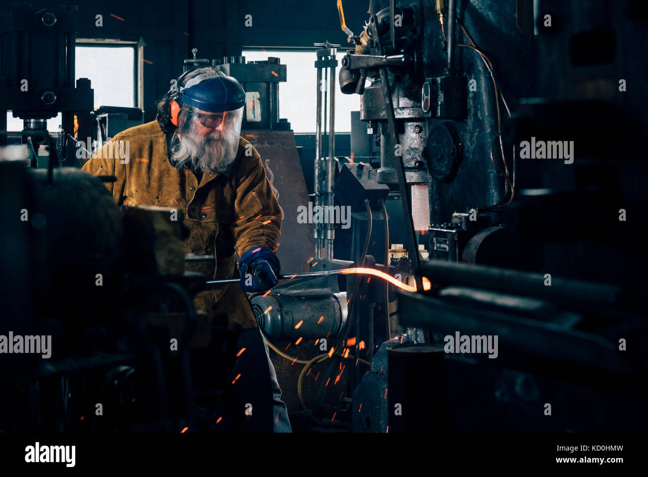 Blacksmith shaping red hot metal rod in workshop Stock Photo - Alamy