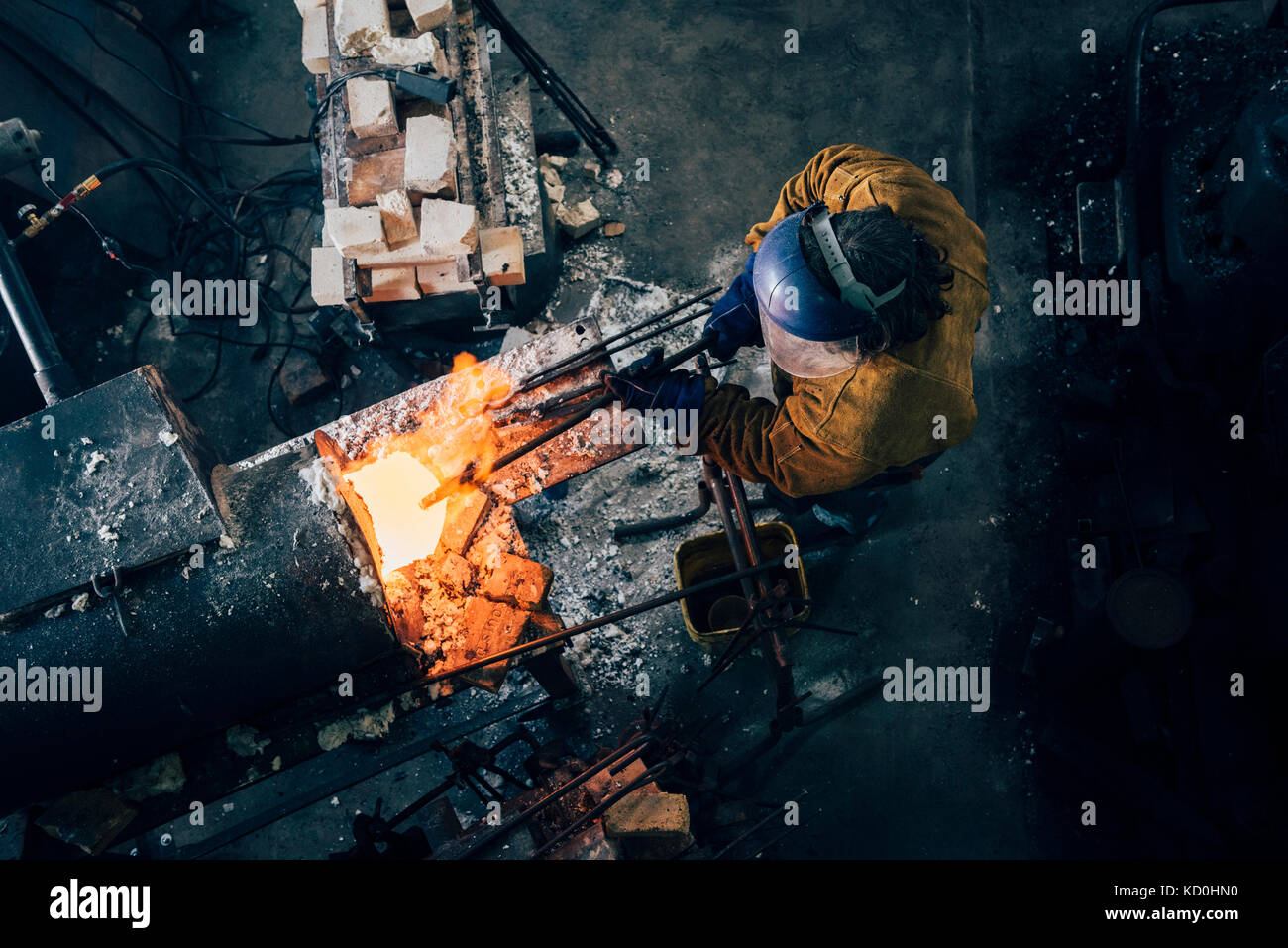Overhead view of blacksmith shaping red hot metal rod in workshop ...