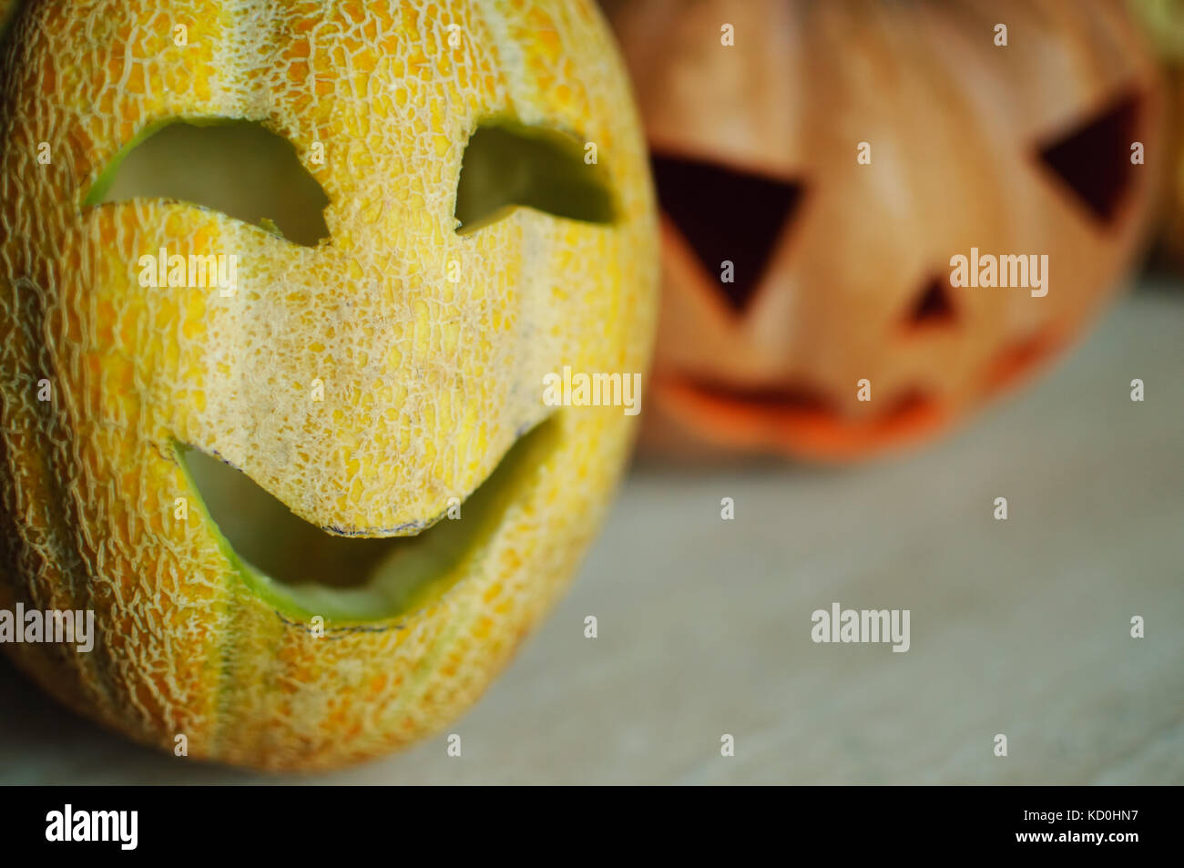 Three jack-o'-lanterns from pumpkin and melons on kitchen table ...