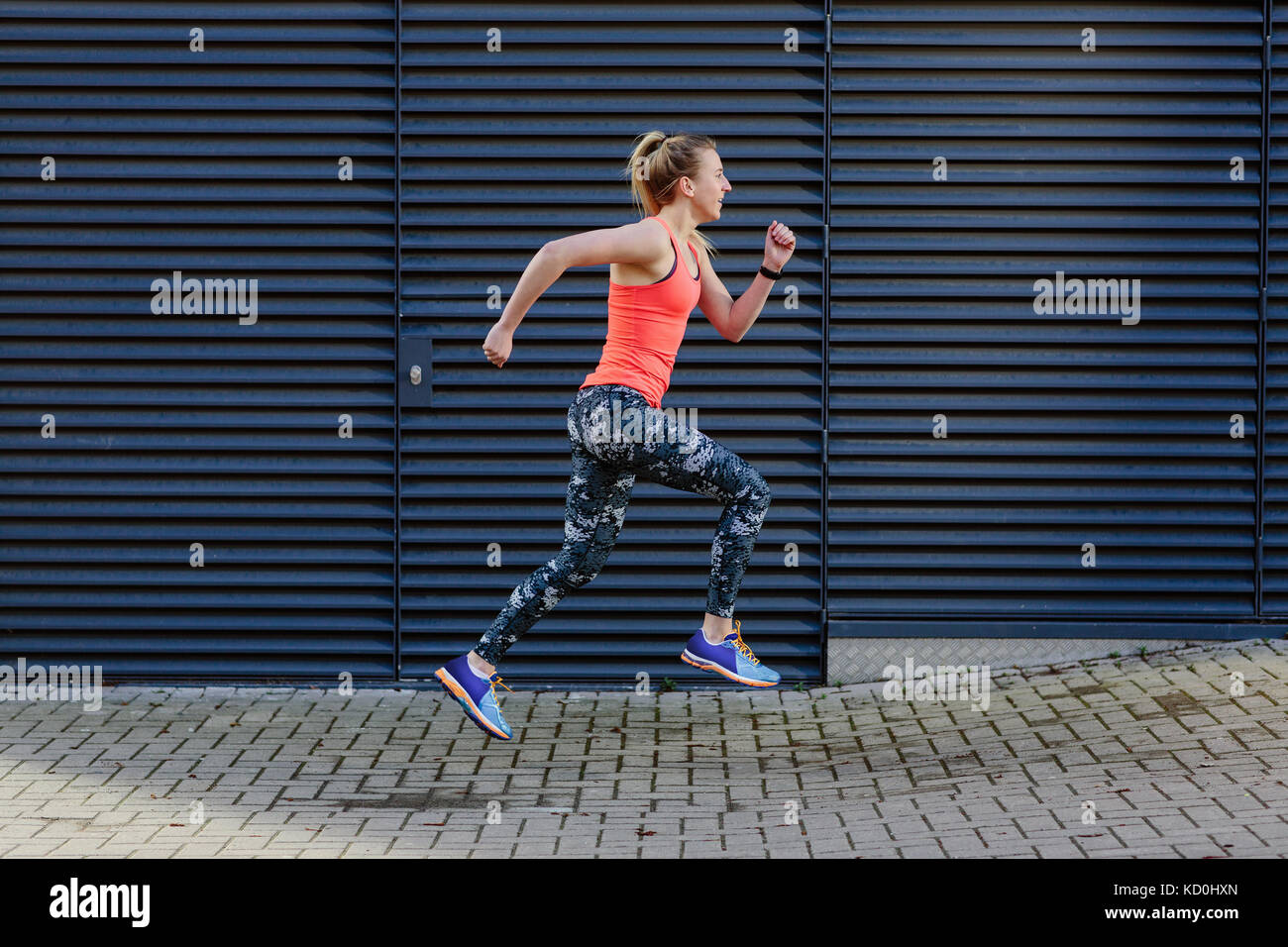 Young female runner speed running along sidewalk Stock Photo - Alamy