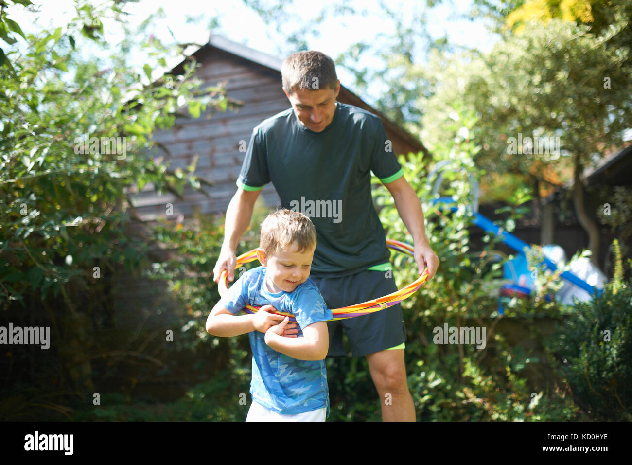 Boy and father playing with plastic hoop in garden Stock Photo - Alamy