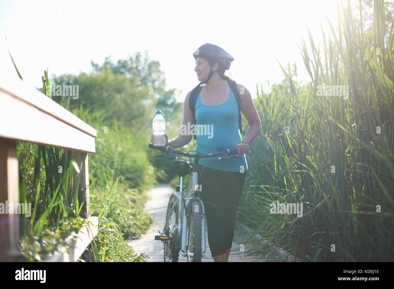 Cyclist walking bike on path through tall grass Stock Photo - Alamy