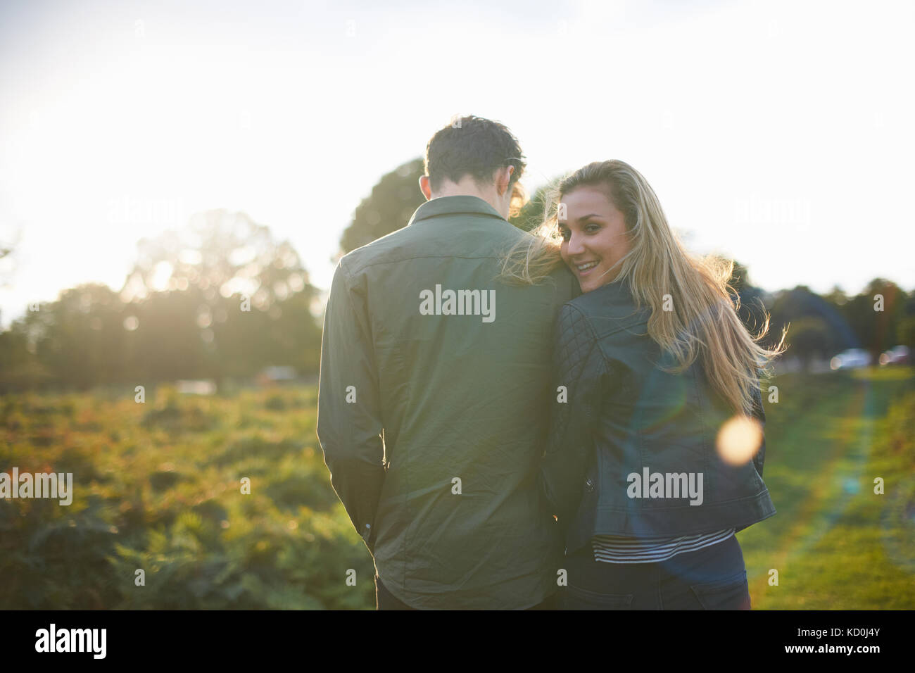 Rear view of young couple strolling arm in arm in field Stock Photo - Alamy