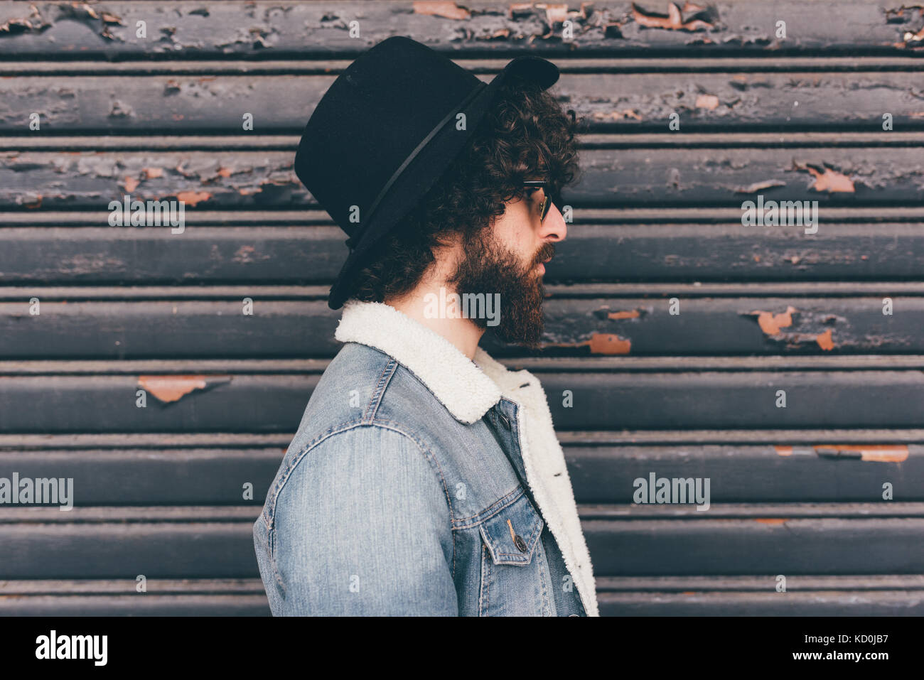 Profile of young man, standing in front of shutter Stock Photo - Alamy