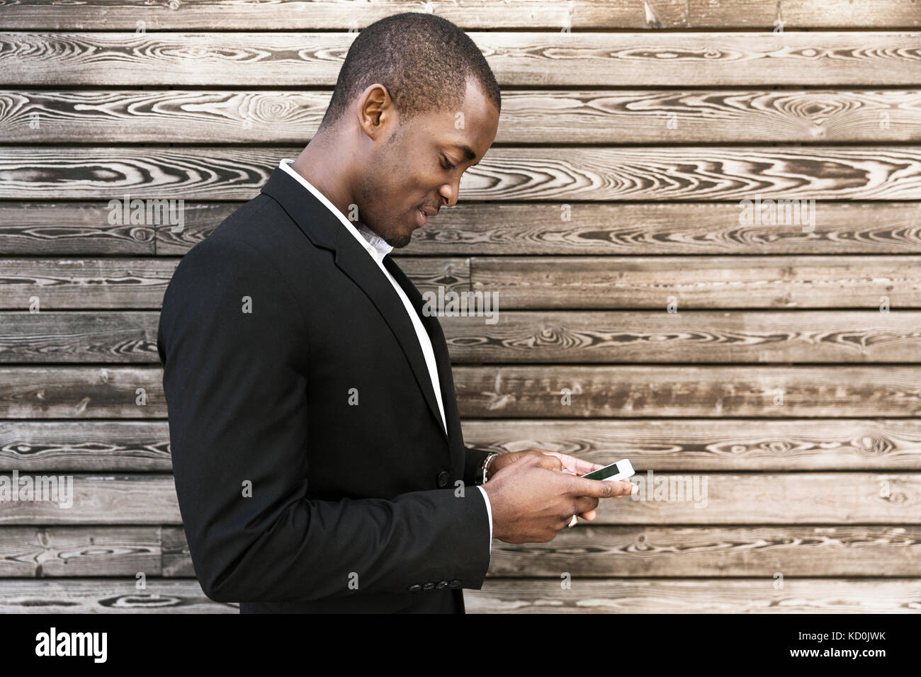 Man using mobile phone by wood paneling Stock Photo - Alamy