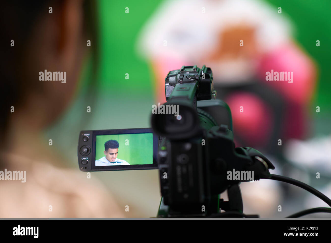 Over shoulder view of college students practicing in TV studio with ...