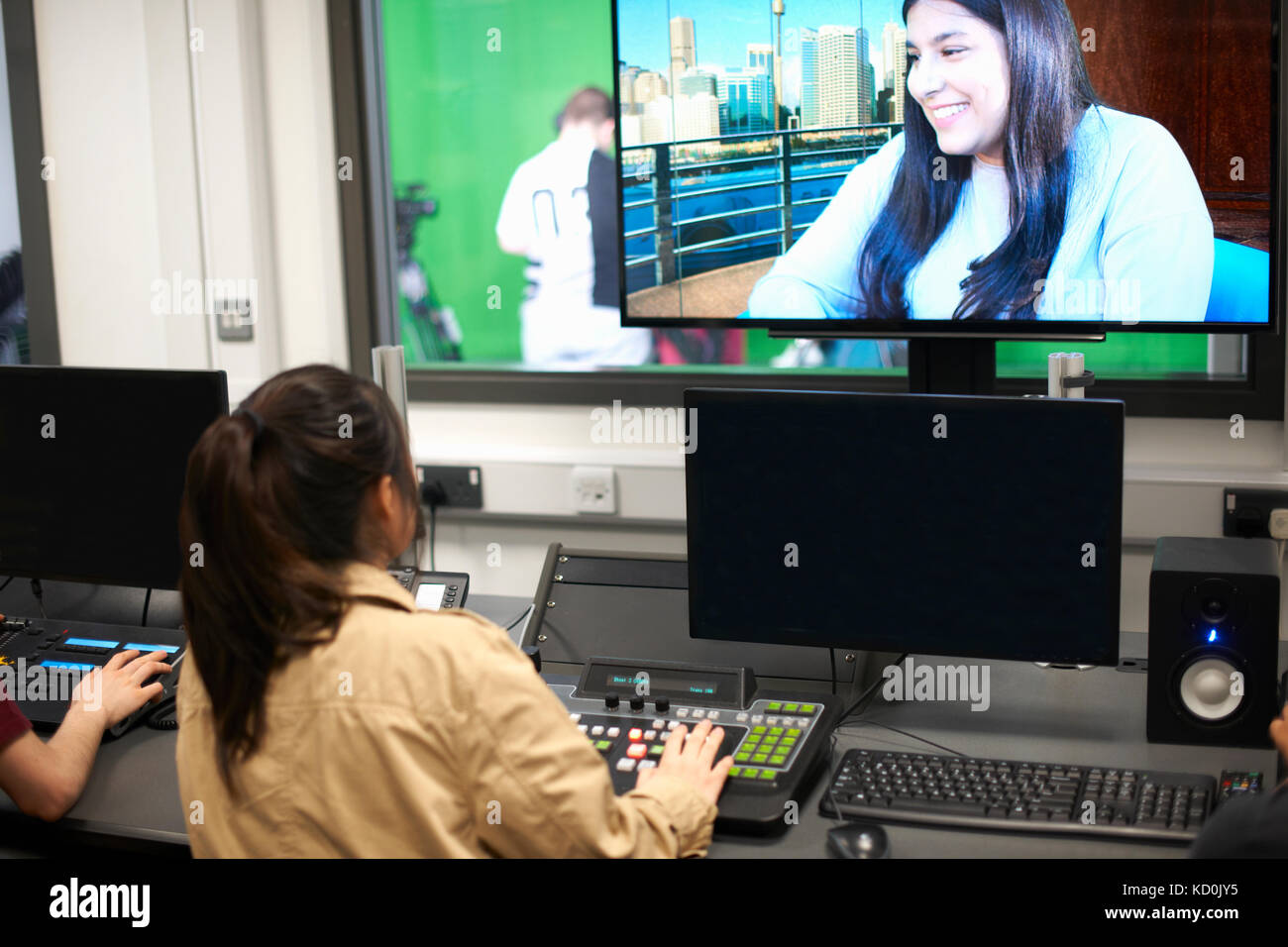 Young male and female college students at mixing desk watching TV ...
