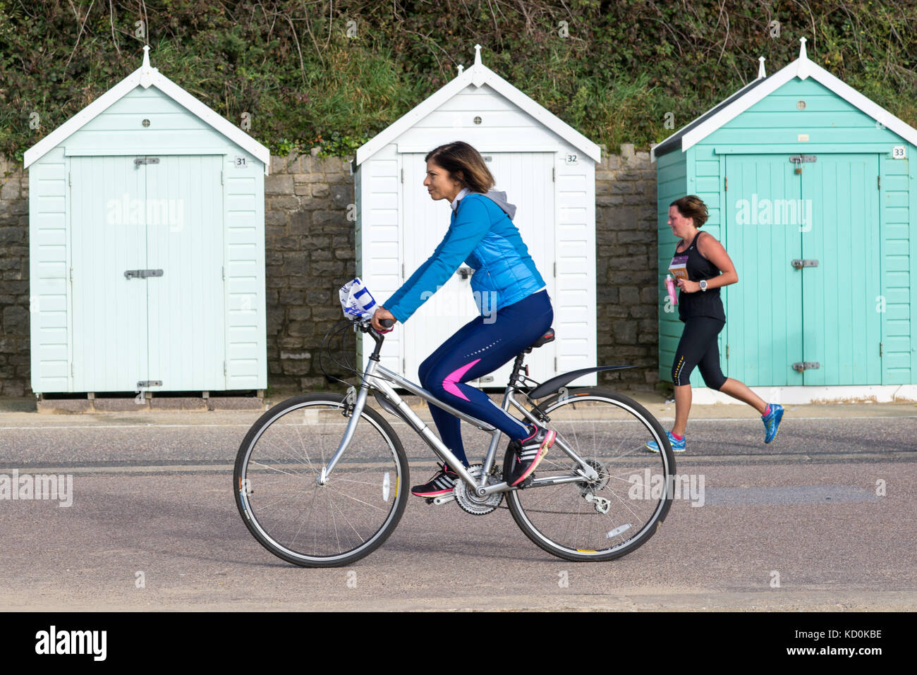 A girl on a bicycle passing a woman running Stock Photo - Alamy