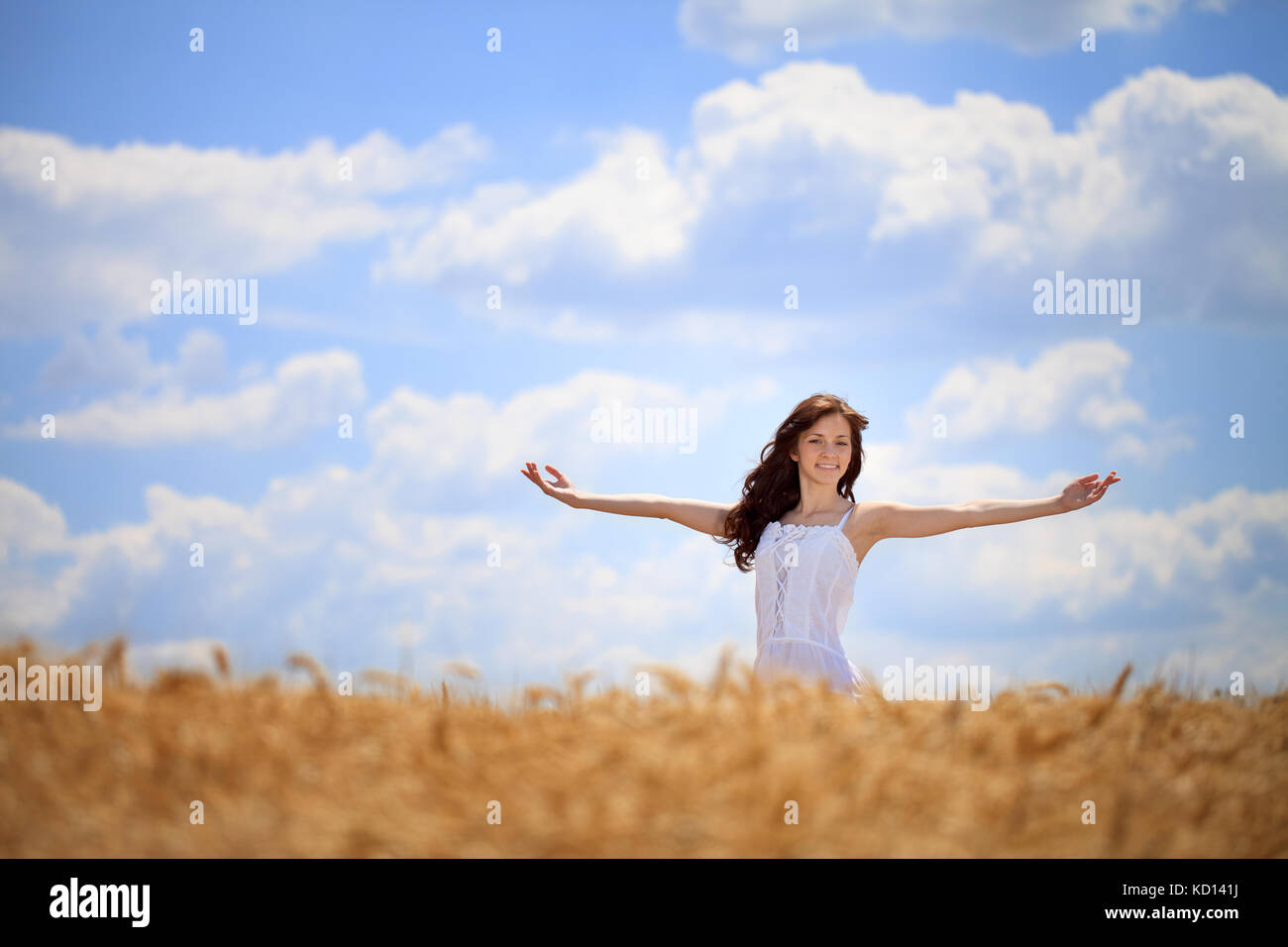 Woman standing with outstretched arms in wheat field , freedom concept ...