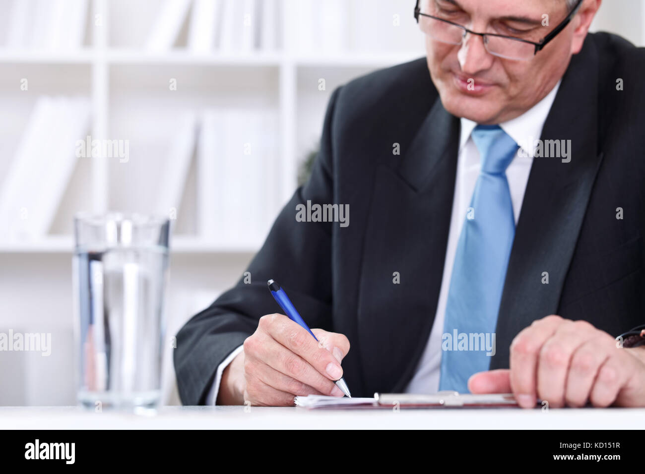 Mature business executive writing on papers at office desk Stock Photo ...