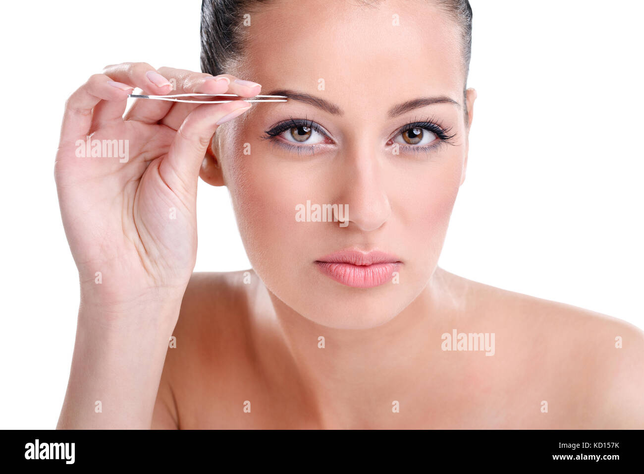 Beautiful young woman plucking eyebrows, looking at camera as mirror ...