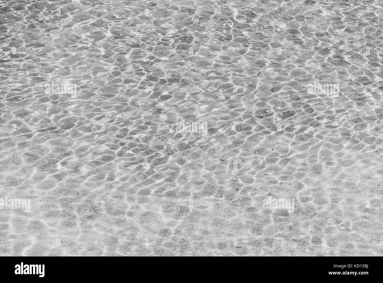 Refraction of light in clear water with small waves. Black and white ...