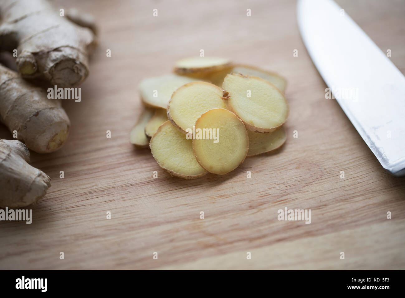 Ginger root and ginger slices with knife on cutting board Stock Photo ...