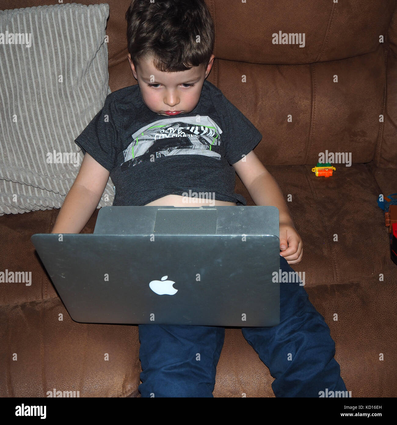 young child playing on a mac laptop at home while surfing the internet ...