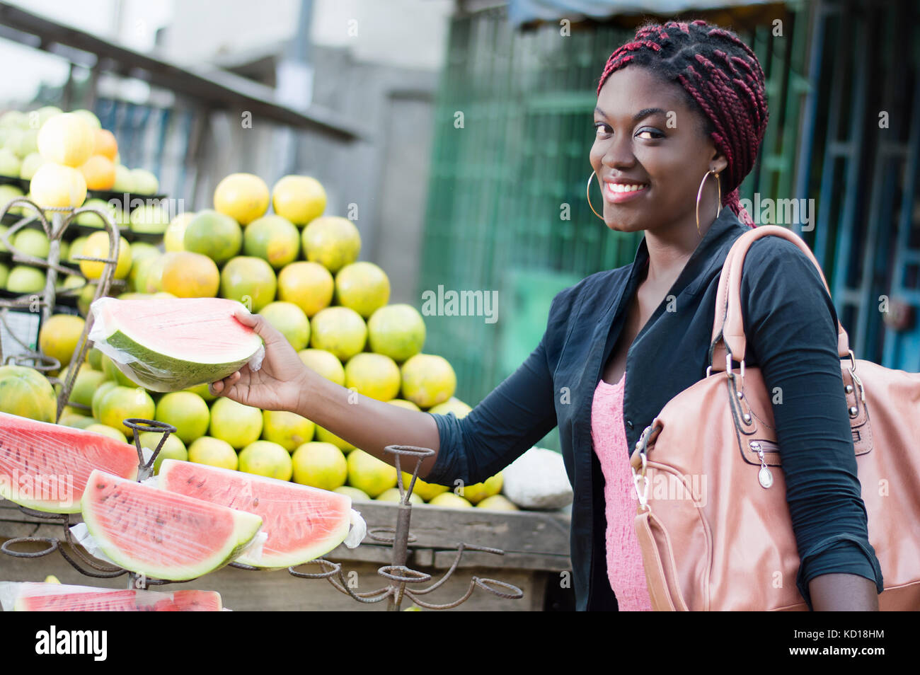 smiling young woman grabs a slice of ripe fruit in a street market ...