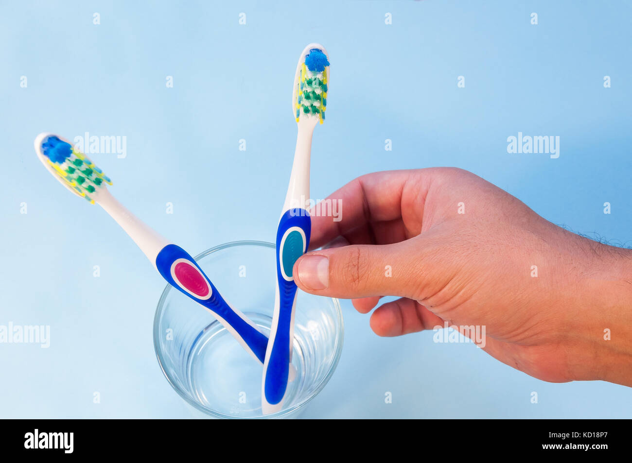 Two toothbrushes in a glass. A man's hand takes one toothbrush Stock ...